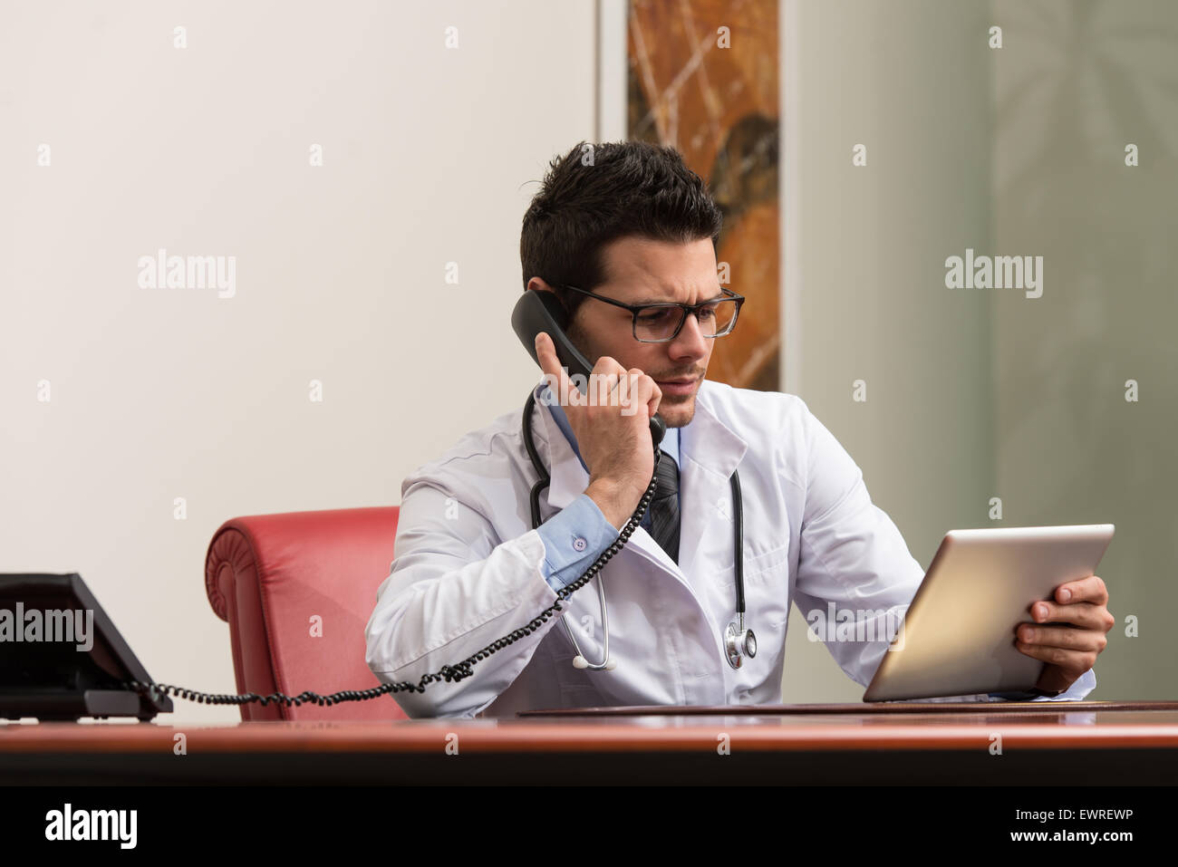 Young Doctor Working At His Computer While Talking On The Phone Stock ...