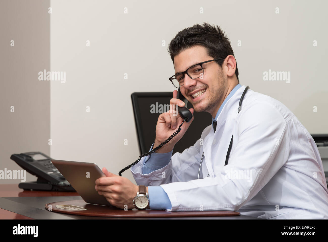 Young Doctor Working At His Computer While Talking On The Phone Stock ...