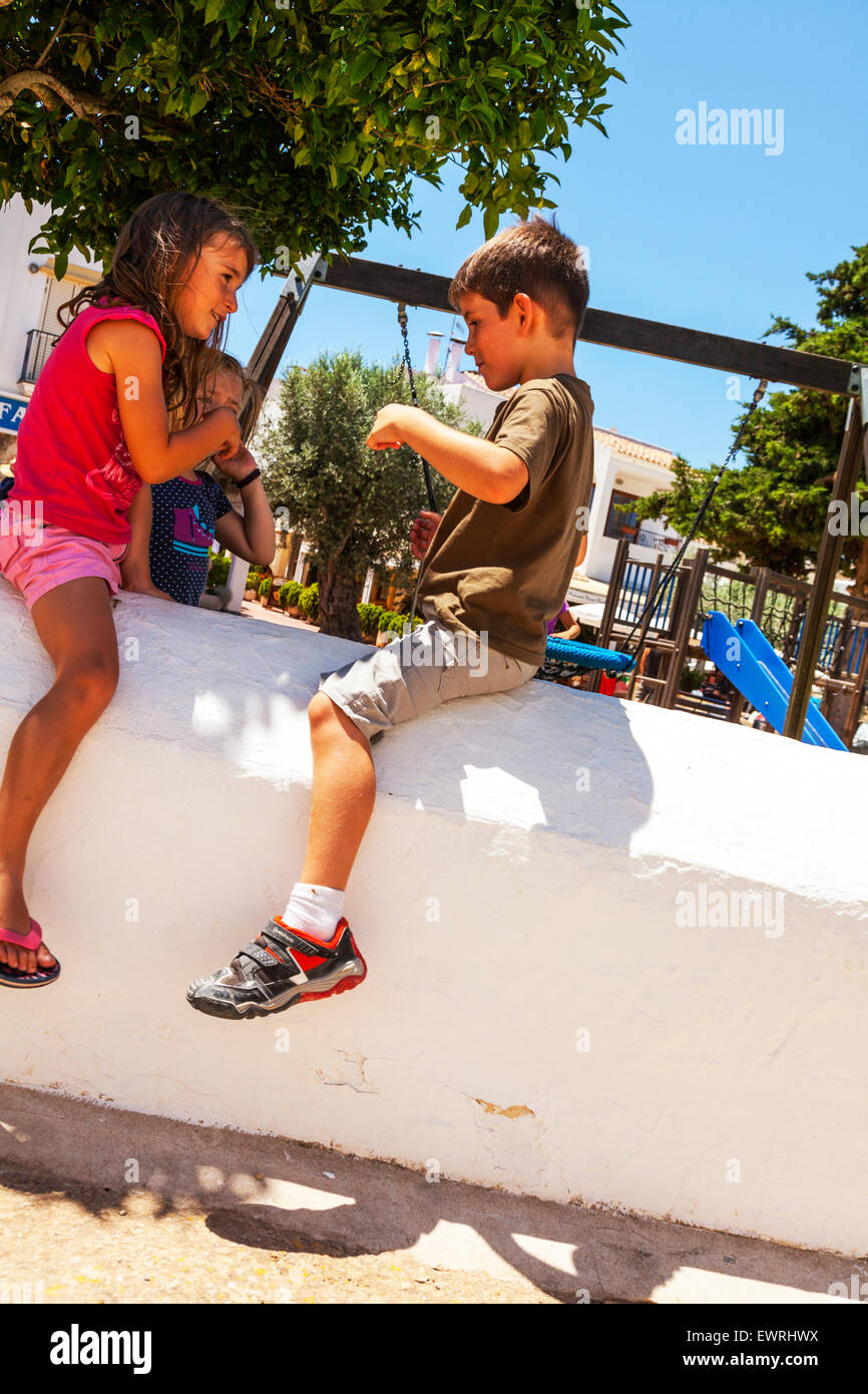 Kids playing sat on wall youngsters fun time together outside Ibiza ...