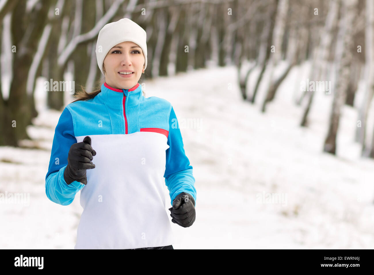 Young smiling athlete woman jogging in winter park. Pretty girl running ...