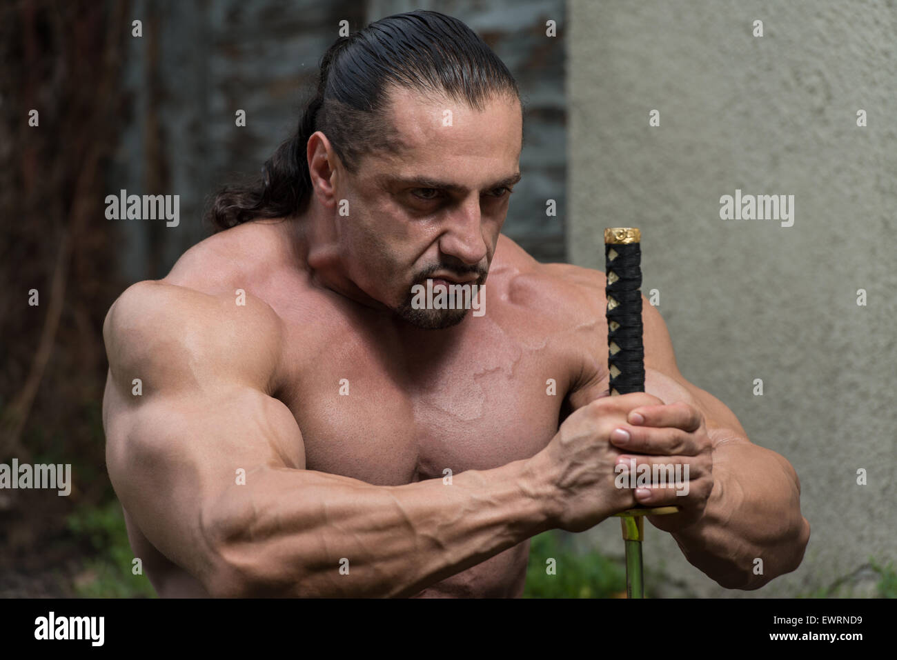 Action Hero Muscled Man Holding A Ancient Sword - Standing In Forest ...