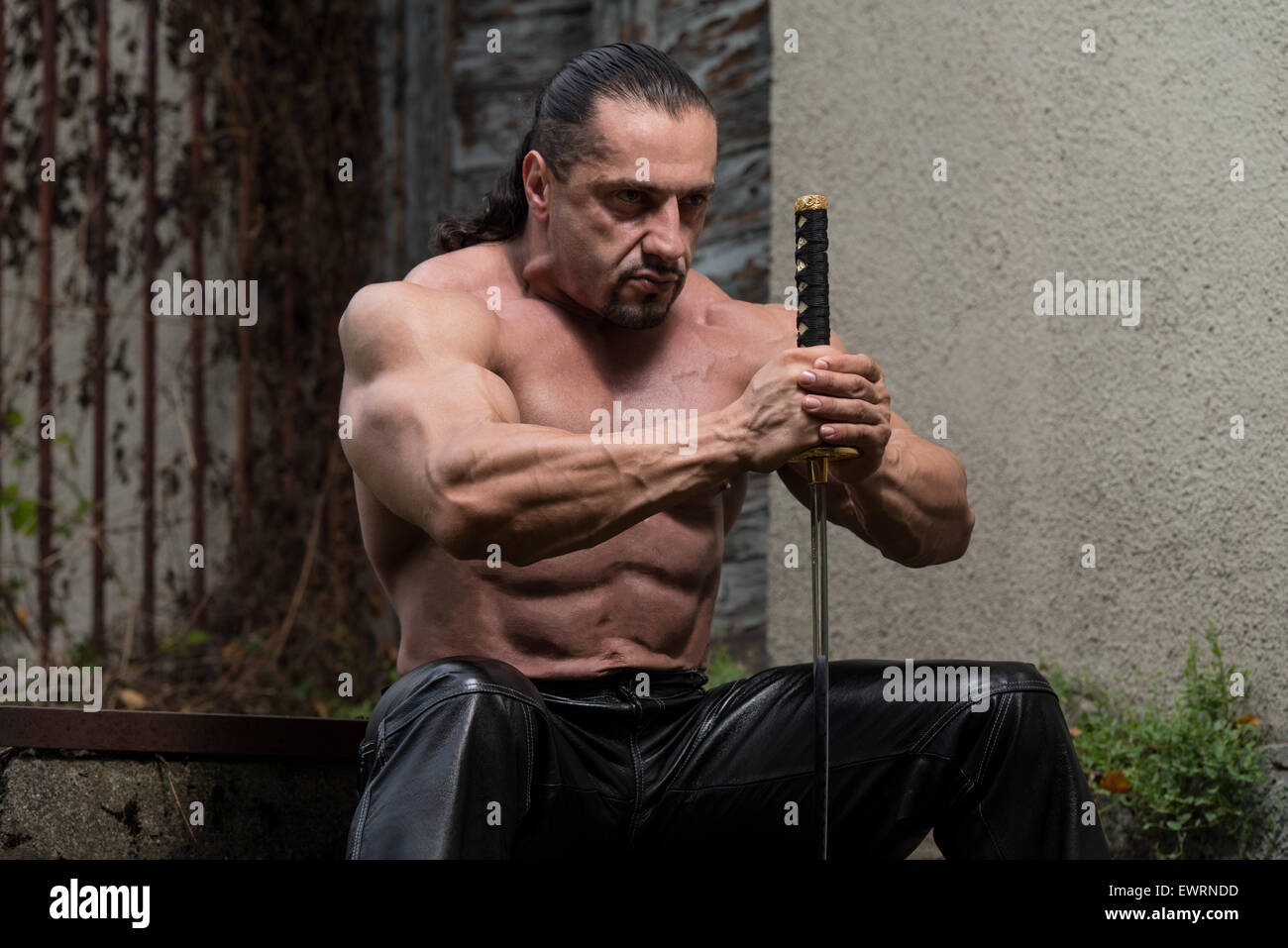Action Hero Muscled Man Holding A Ancient Sword - Standing In Forest ...