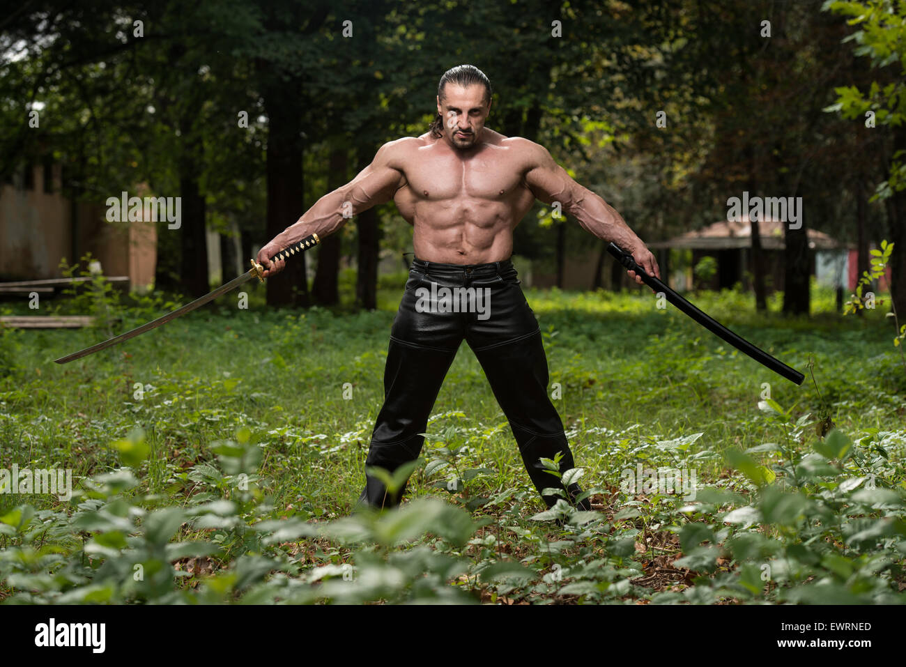 Action Hero Muscled Man Holding A Ancient Sword - Standing In Forest ...