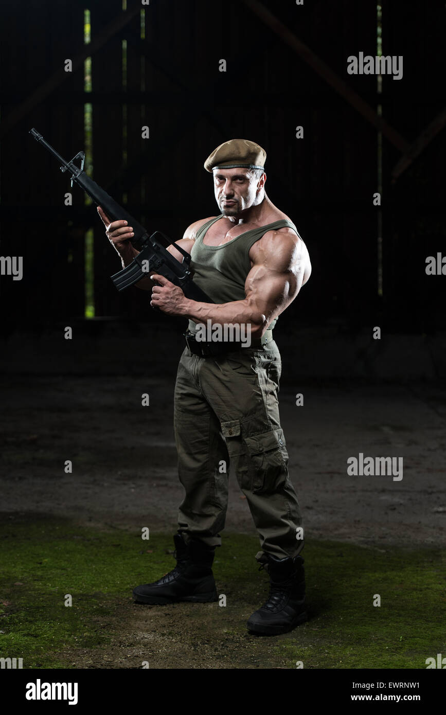 Action Hero Muscled Man Holding Machine Gun - Standing In Abandoned ...