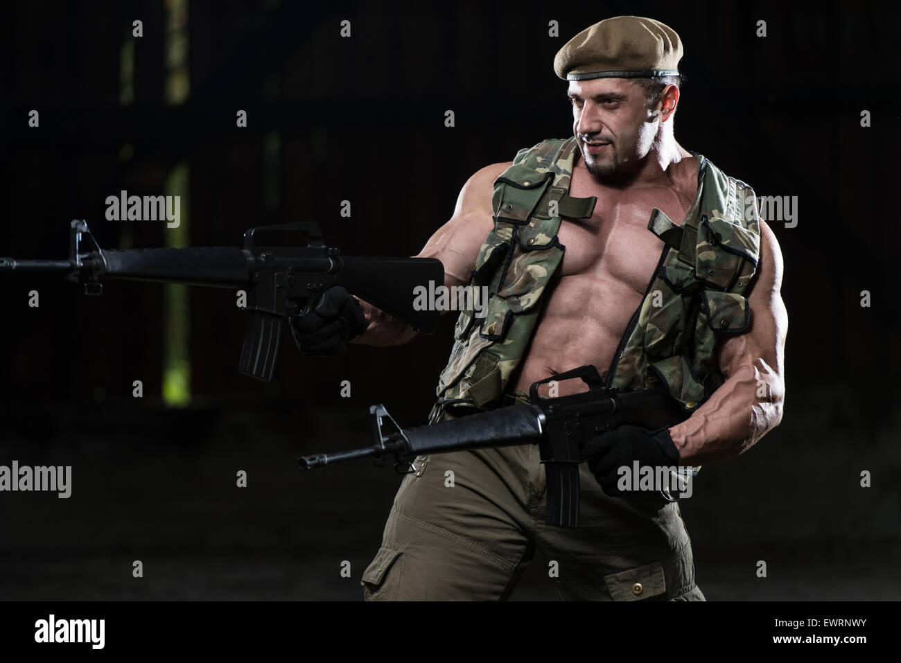 Action Hero Muscled Man Holding Machine Guns - Standing In Abandoned ...