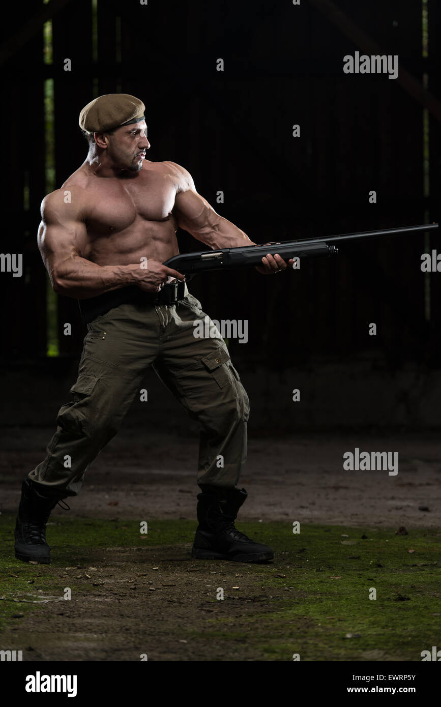 Action Hero Muscled Man Holding Machine Gun - Standing In Abandoned ...