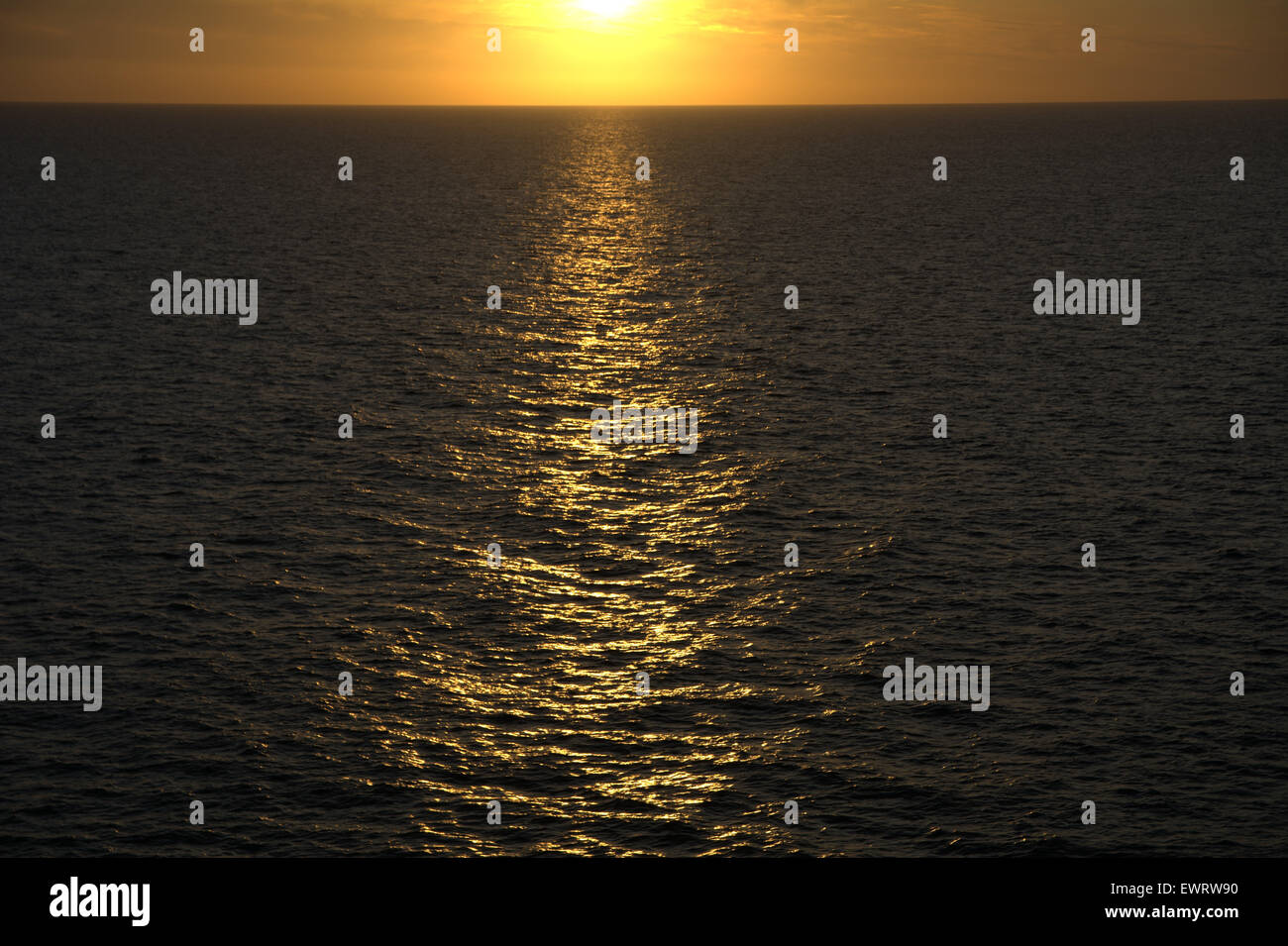 The setting sun reflecting off the waves over an expanse of water Stock ...