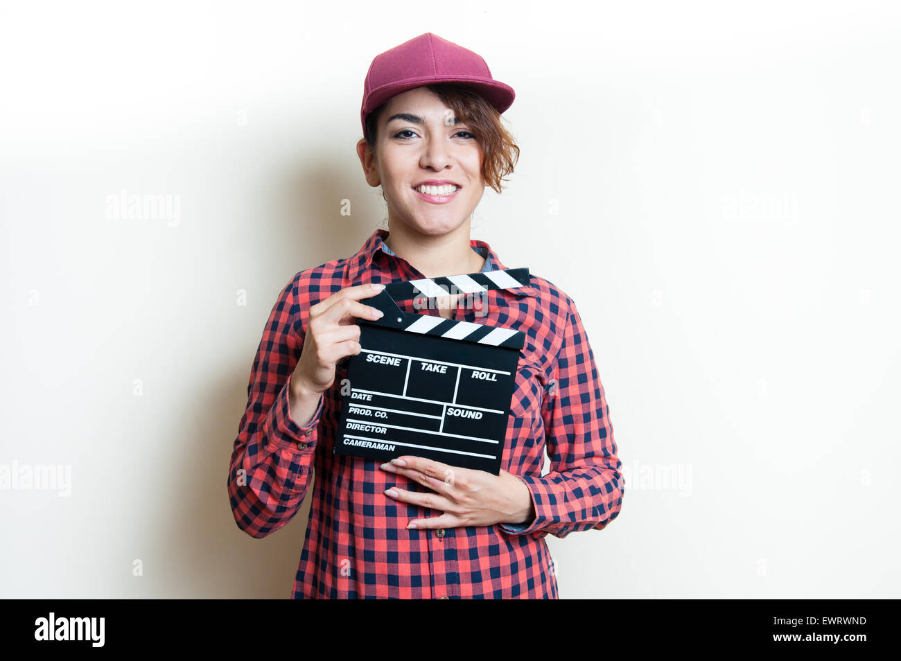 Girl in red shirt and cap smiling and showing movie clapper on white ...