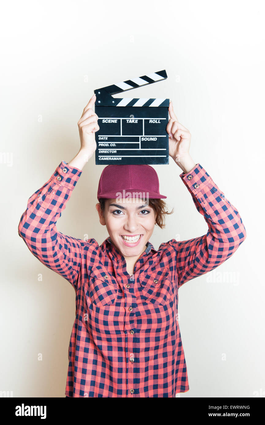Girl in red shirt and cap smiling and showing movie clapper on her head ...