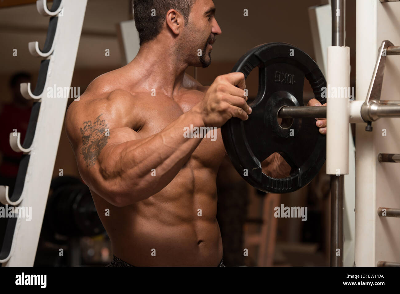 Body Builder Putting Weights On Bar In Gym Stock Photo - Alamy