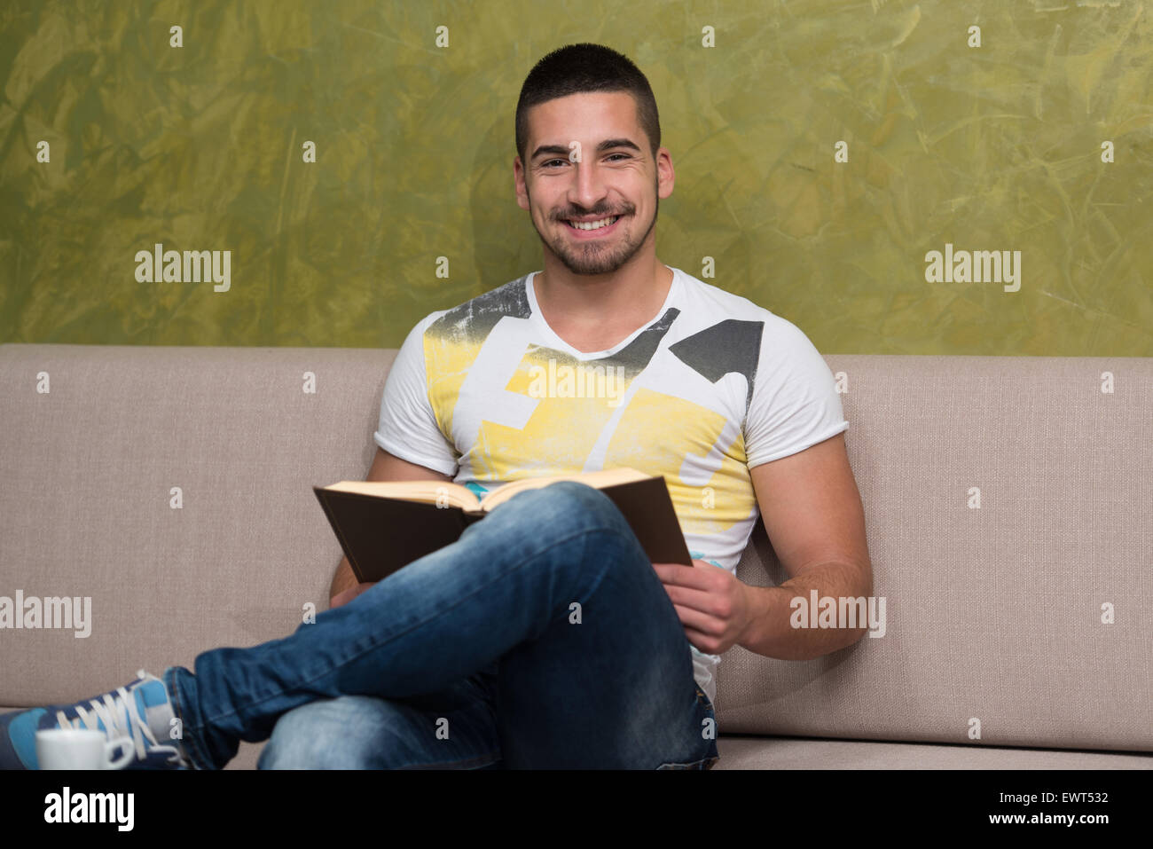 Young Male Student Drinking And Reading Book In Cafeteria Stock Photo ...