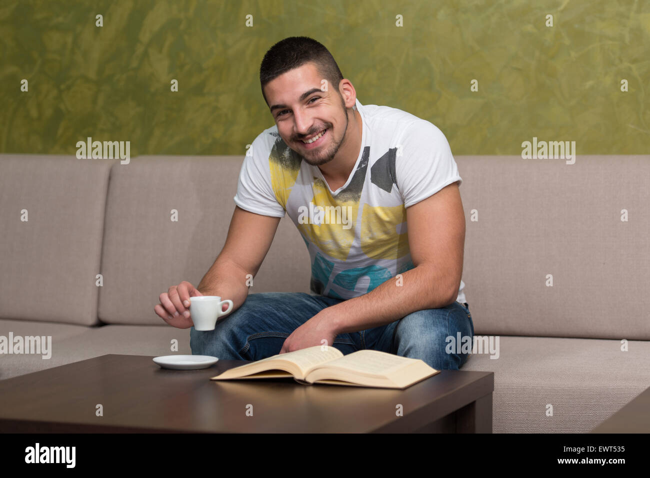 Young Male Student Drinking And Reading Book In Cafeteria Stock Photo ...