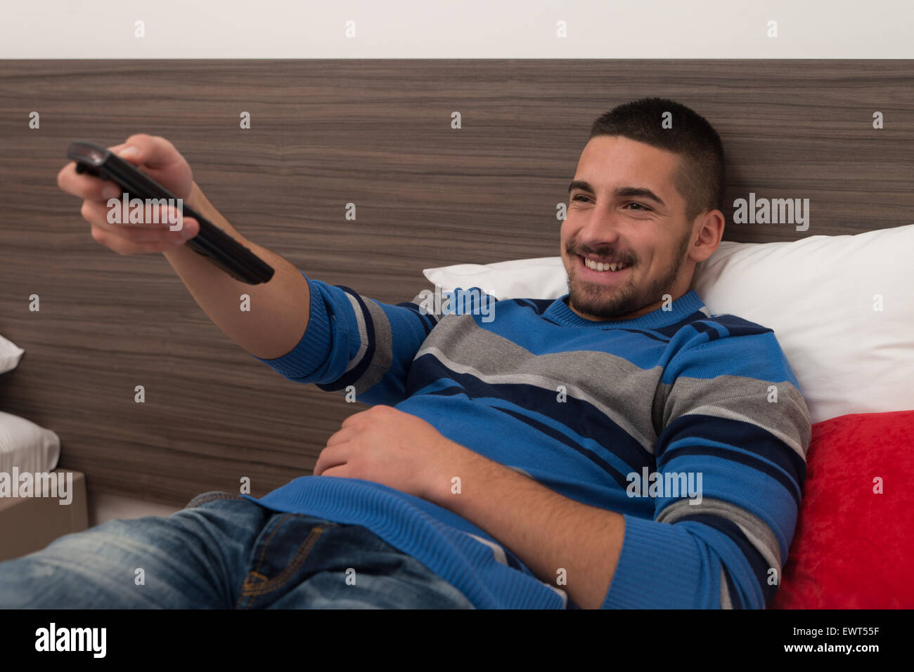 Handsome Young Man Watching Television Lying On Bed With The Remote ...