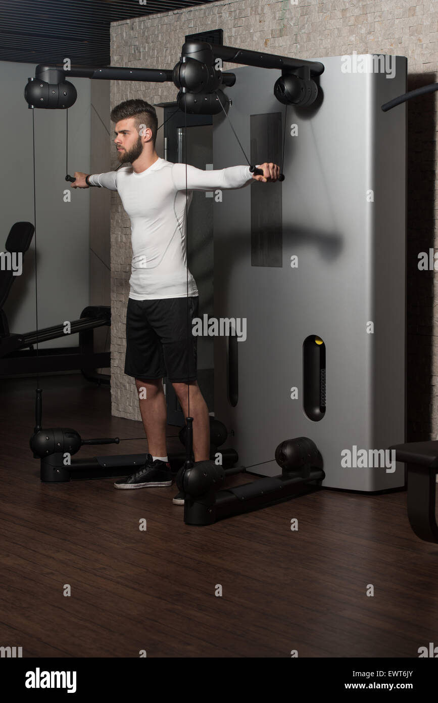 Handsome Man Is Working On His Shoulders With Cable Crossover In A ...