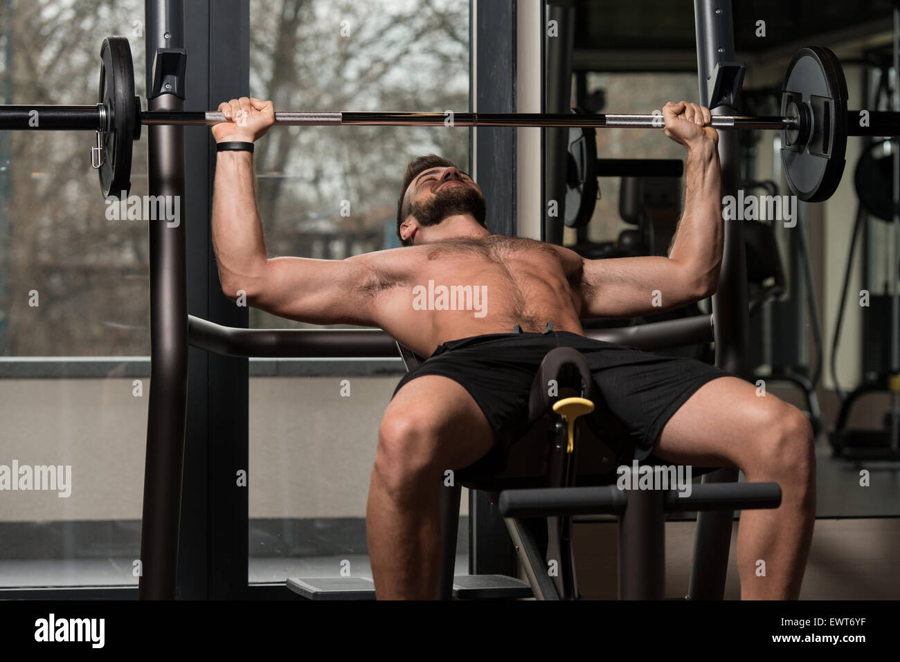 Handsome Man Is Working Out Chest With Barbell In A Modern Gym Stock ...