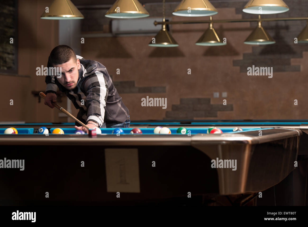 Young Man Lining To Hit Ball On Pool Table Stock Photo - Alamy
