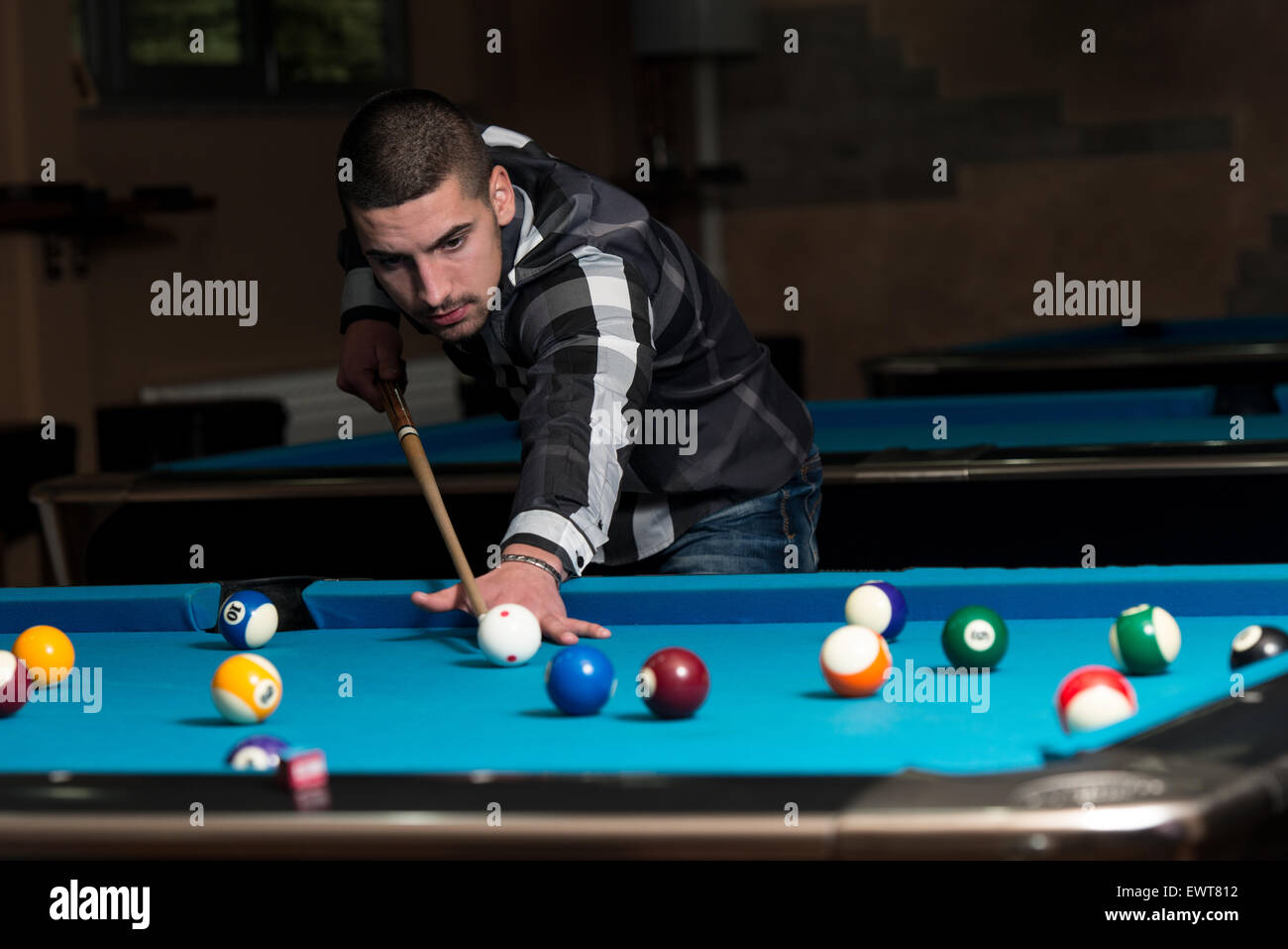 Young Man Lining To Hit Ball On Pool Table Stock Photo - Alamy