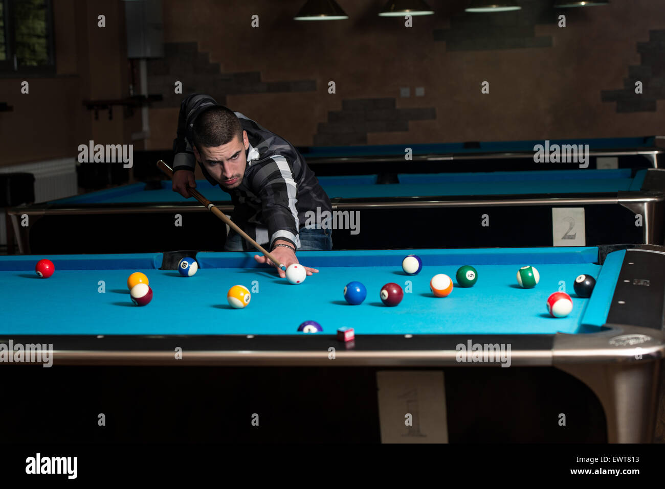 Young Man Lining To Hit Ball On Pool Table Stock Photo - Alamy