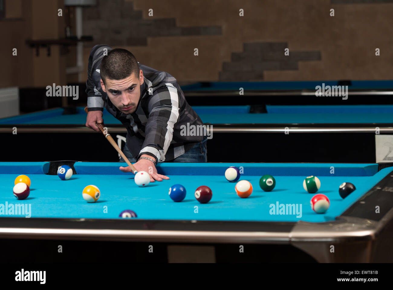 Young Man Lining To Hit Ball On Pool Table Stock Photo - Alamy