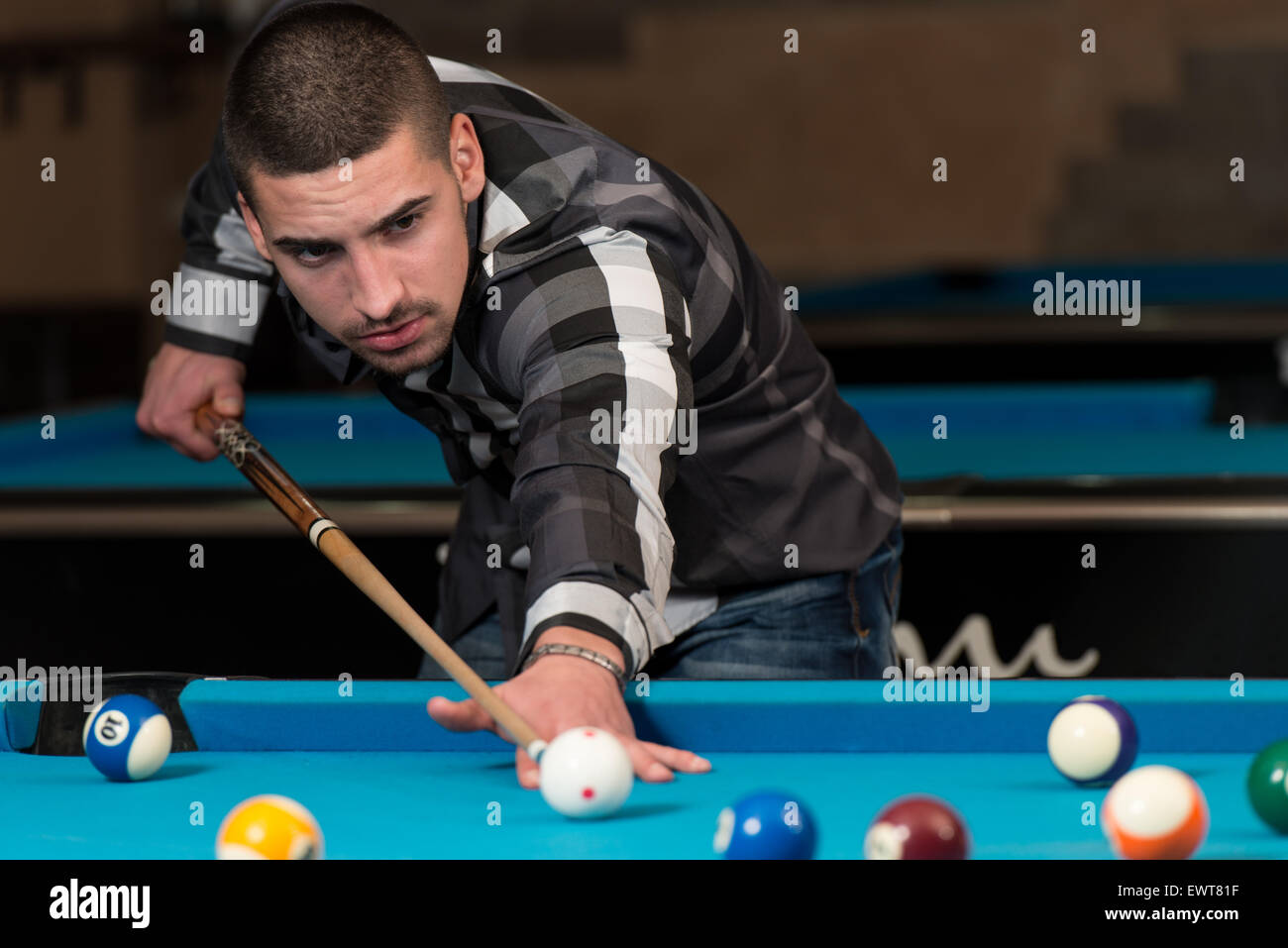 Young Man Lining To Hit Ball On Pool Table Stock Photo - Alamy