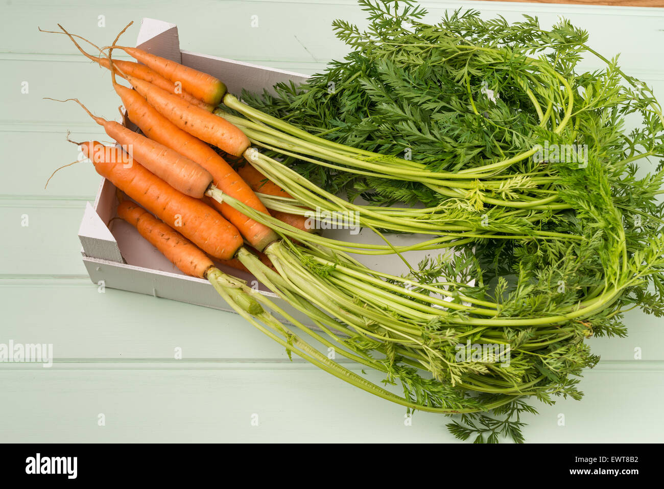 Carrots inside white wooden box on the light green wooden table Stock ...