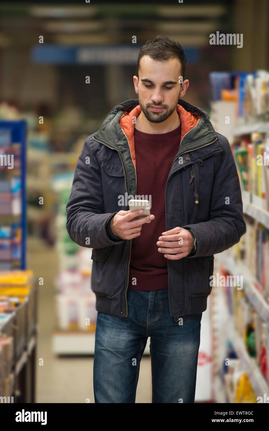 Smiling Young Man Using Mobile Phone While Shopping In Shopping Store ...