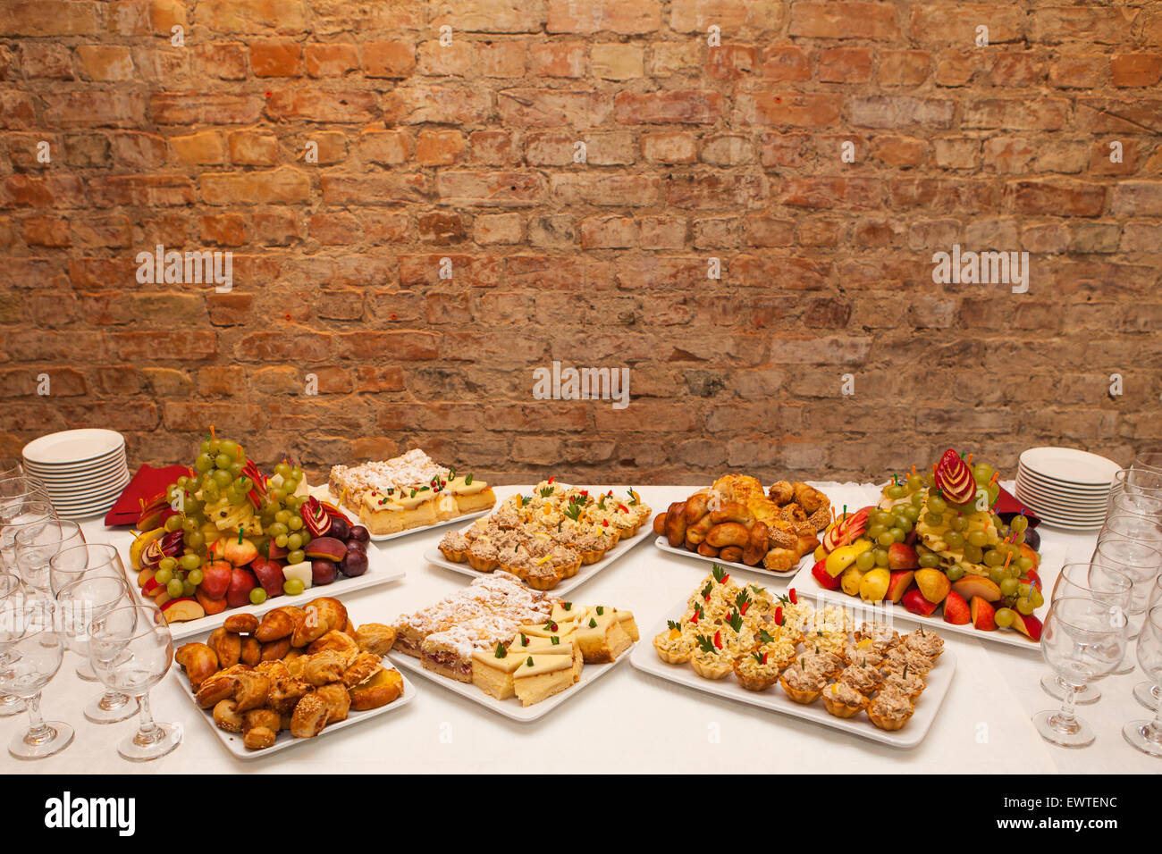 Festive well-laid table with food and drink on brick wall background ...