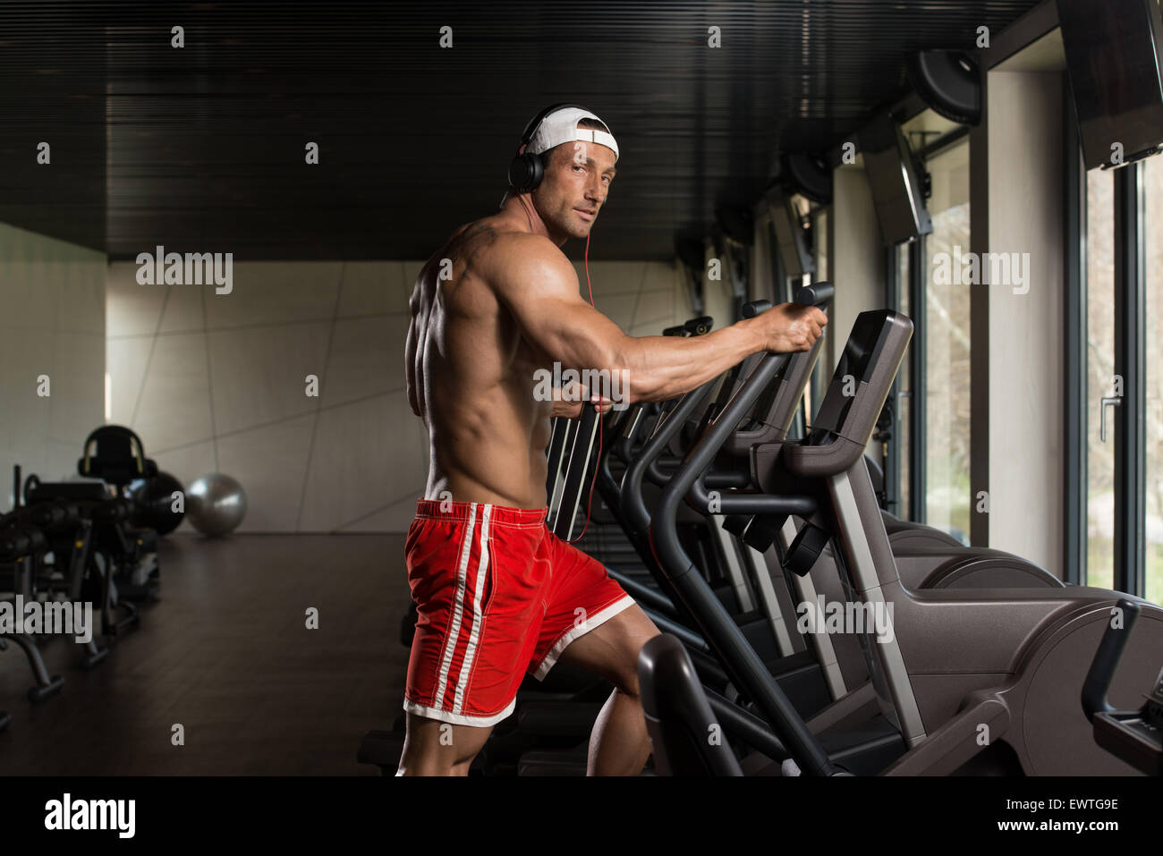 Muscular Mature Man Doing Aerobics Elliptical Walker In Modern Fitness ...