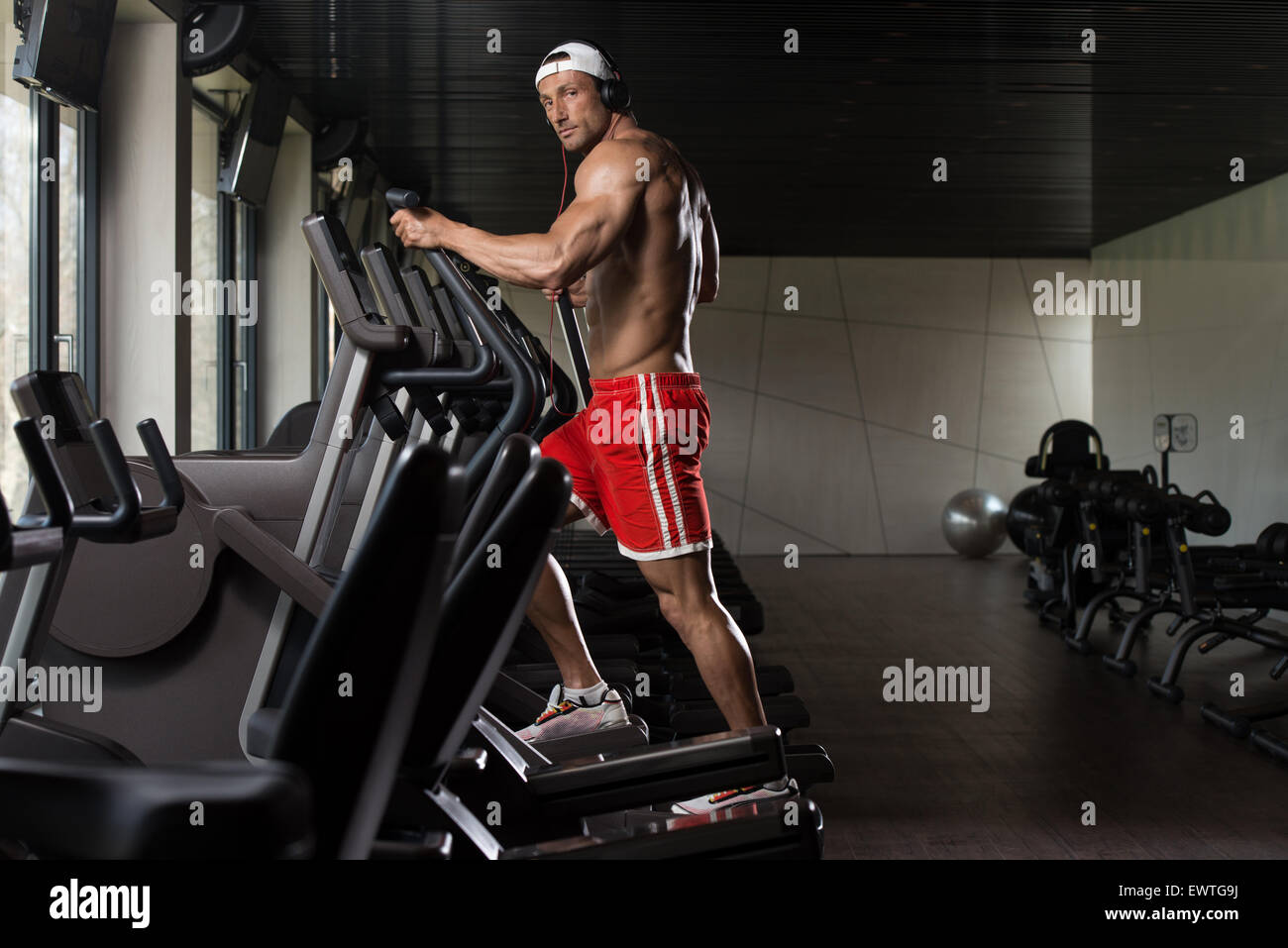 Muscular Mature Man Doing Aerobics Elliptical Walker In Modern Fitness ...