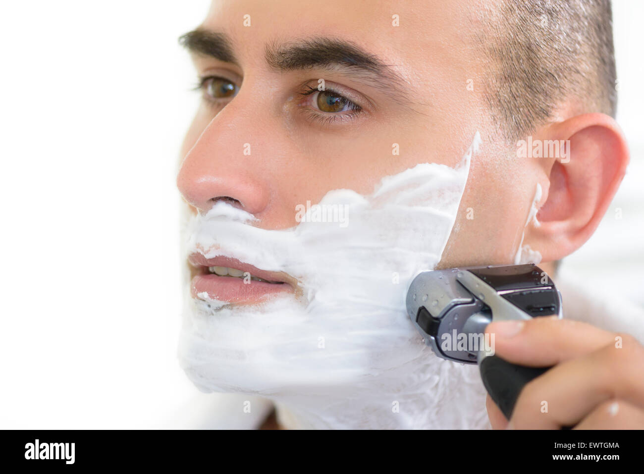 Young man shaving using electric shaver Stock Photo - Alamy