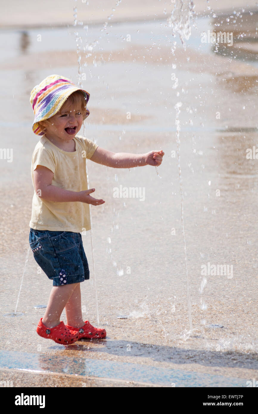Young girl enjoys the cooling water in the new water fountain feature ...