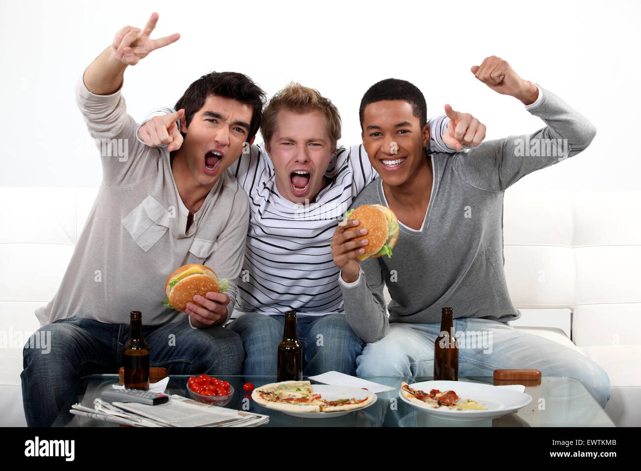 three friends eating while watching television Stock Photo - Alamy