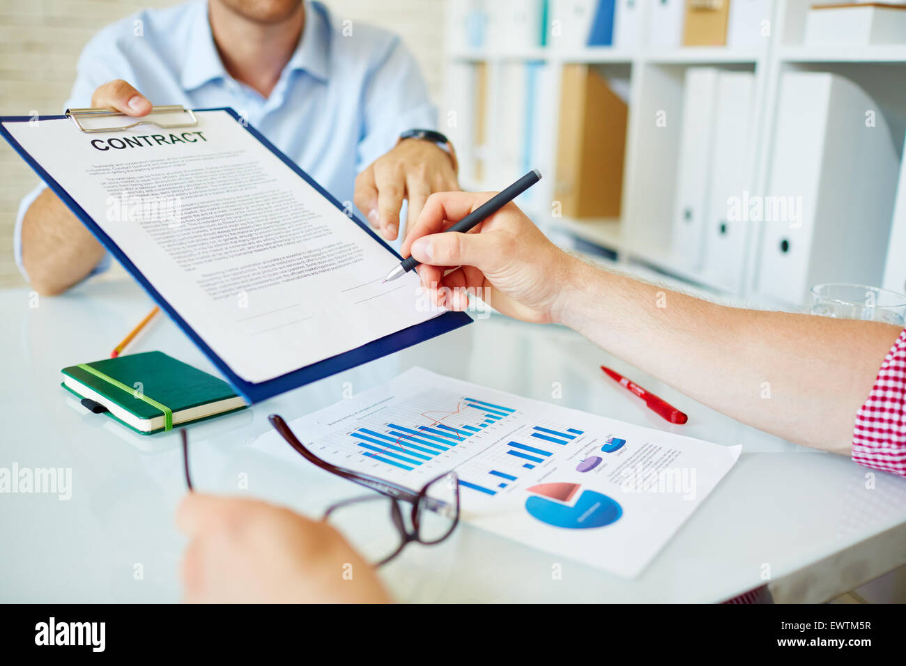 Businessman holding contract while his partner signing it Stock Photo ...