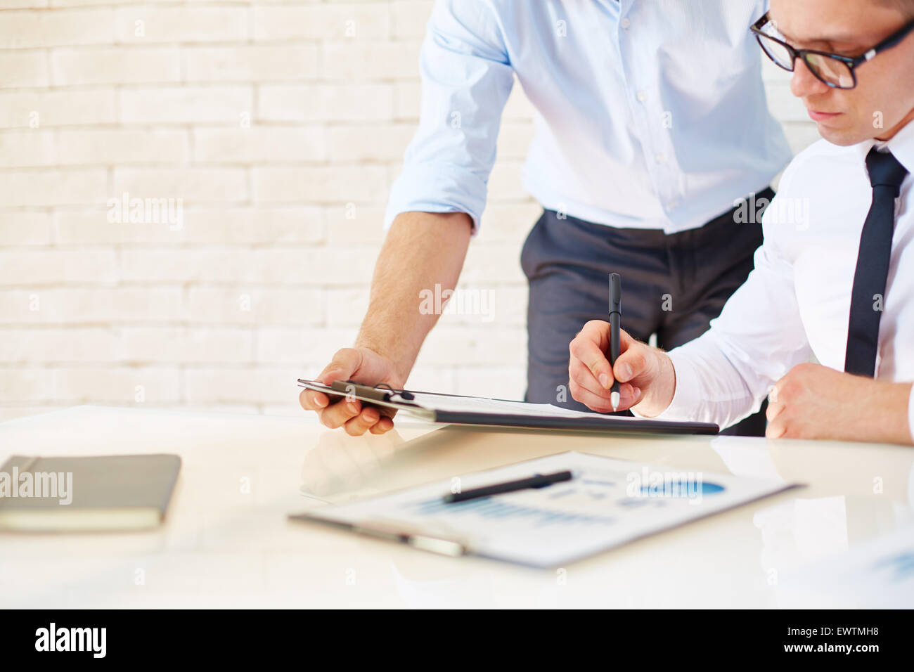 Confident boss signing document held by colleague Stock Photo - Alamy