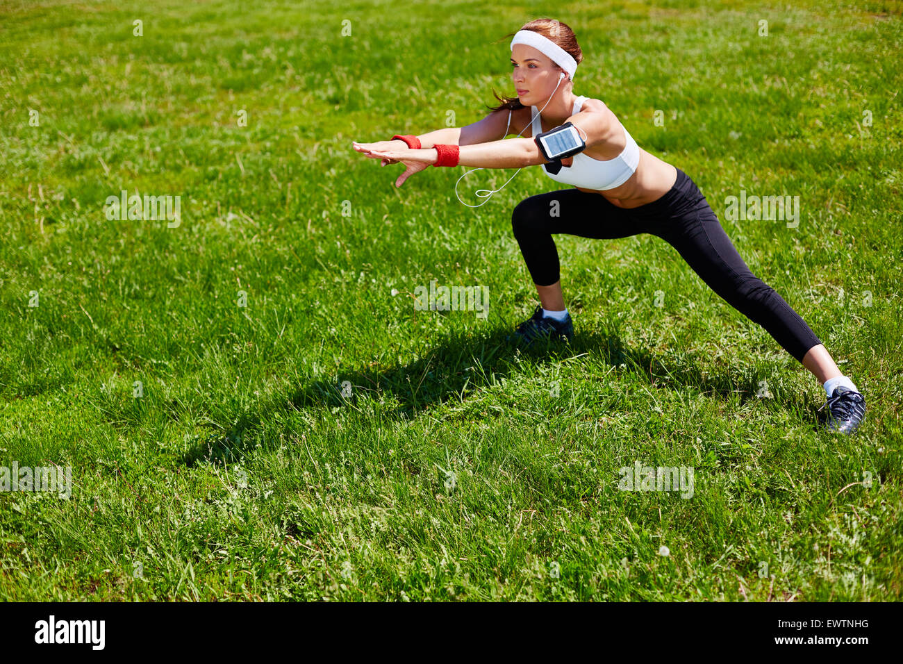 Sporty girl doing stretching exercise on green grass Stock Photo - Alamy