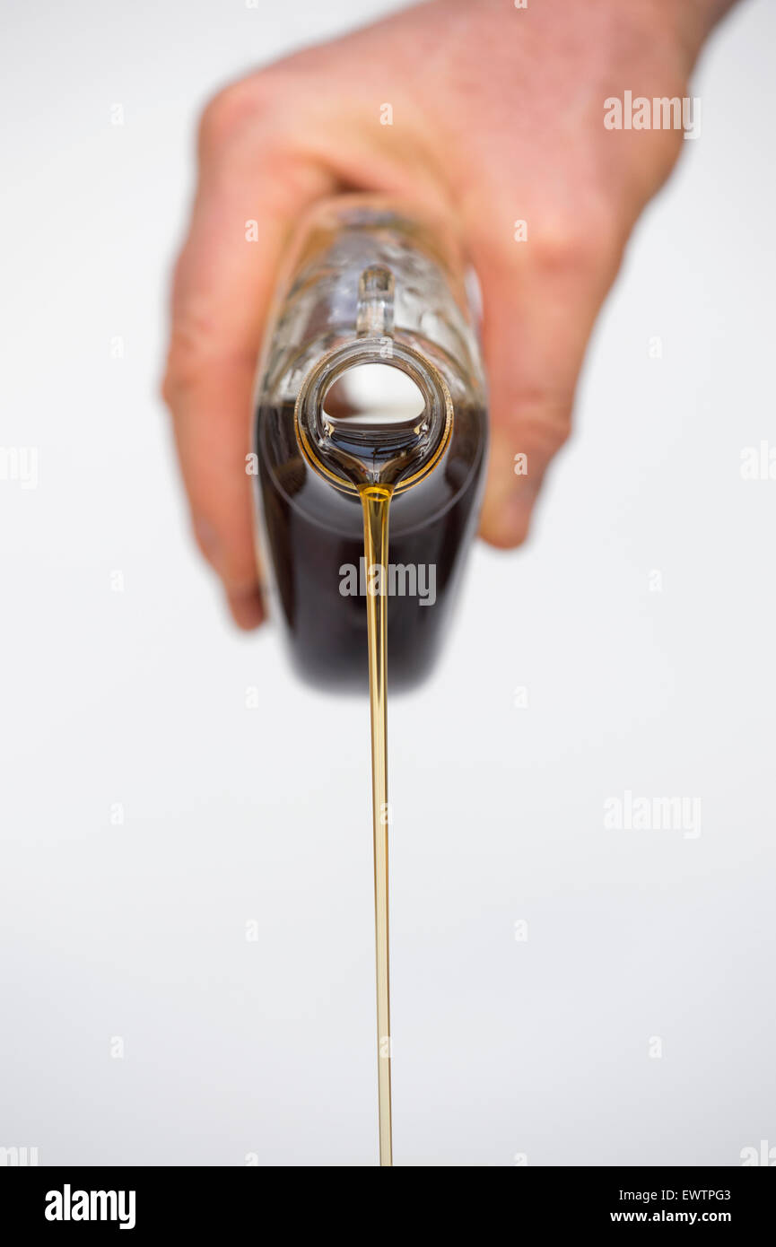 Hand pouring Organic American Maple syrup from a bottle against white ...