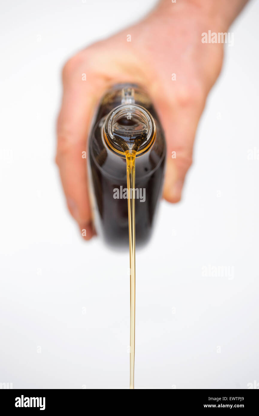 Hand pouring Organic American Maple syrup from a bottle against white ...