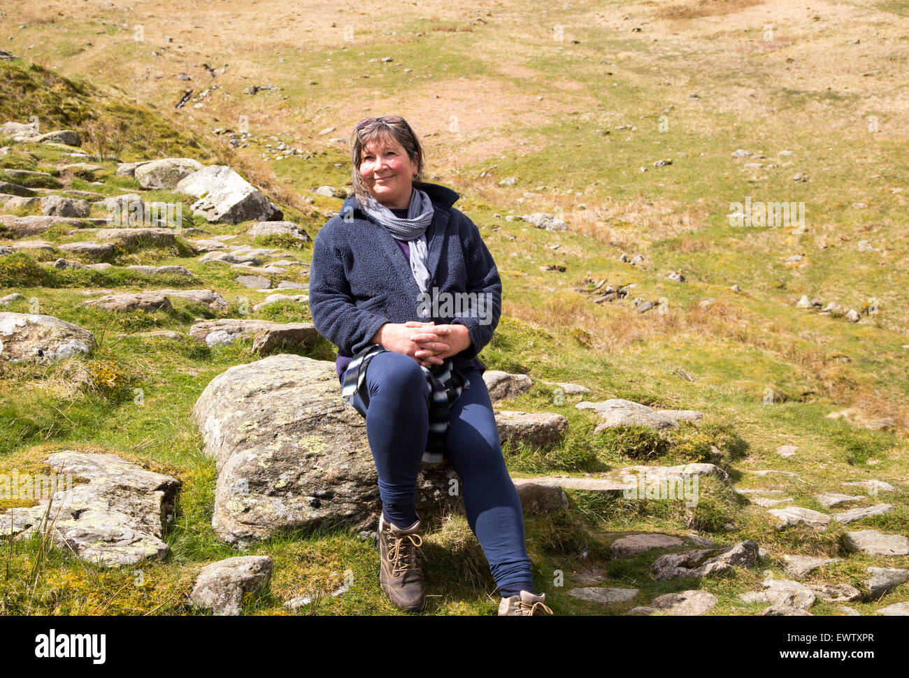 Woman sitting in countryside, Lake District national park, Cumbria ...
