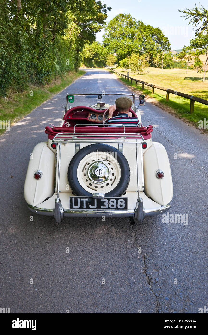 Rear view of white MG TF 1500 classic car being driven down a country ...
