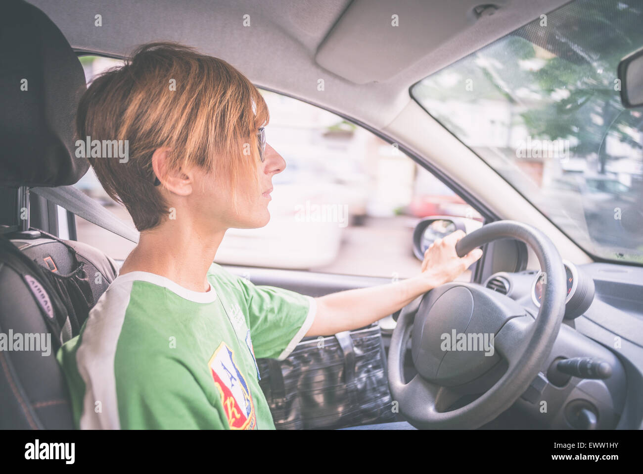 Adult woman driving car with one hand on steering wheel. Interior close ...