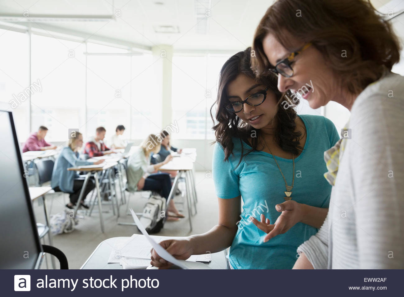 Professor and college student discussing homework in classroom Stock ...