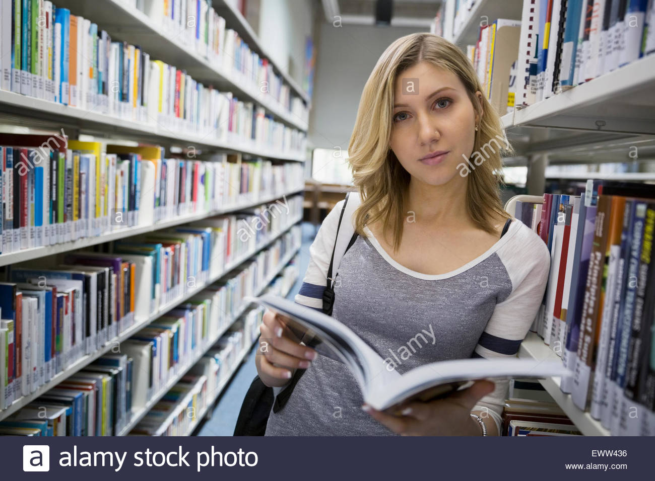 Portrait college student reading book at library bookshelf Stock Photo ...