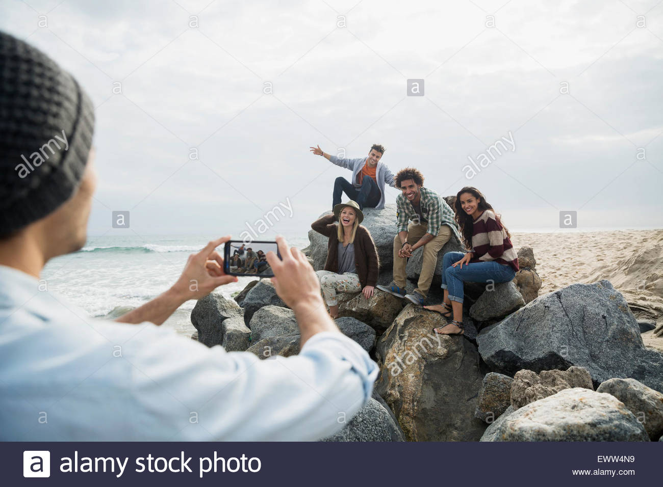 Man standing on rocks by the ocean with arms outstretched hi-res stock ...