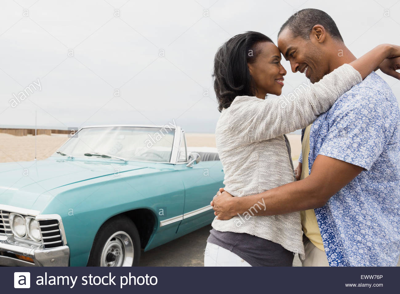 Affectionate couple hugging near convertible at beach Stock Photo - Alamy
