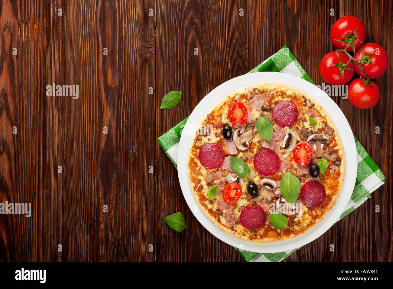 Italian pizza with pepperoni, tomatoes, olives and basil on wooden ...