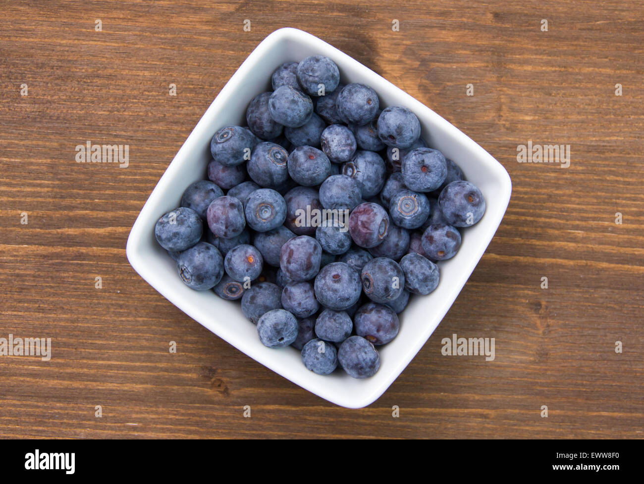 Blueberries on square bowl on wooden table seen from above Stock Photo ...