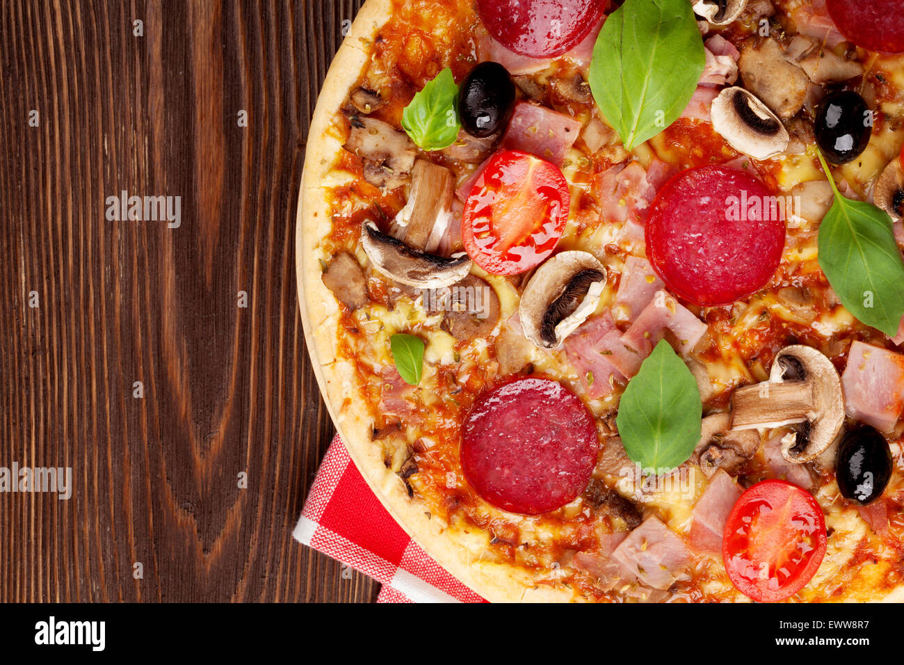 Italian pizza with pepperoni, tomatoes, olives and basil on wooden ...