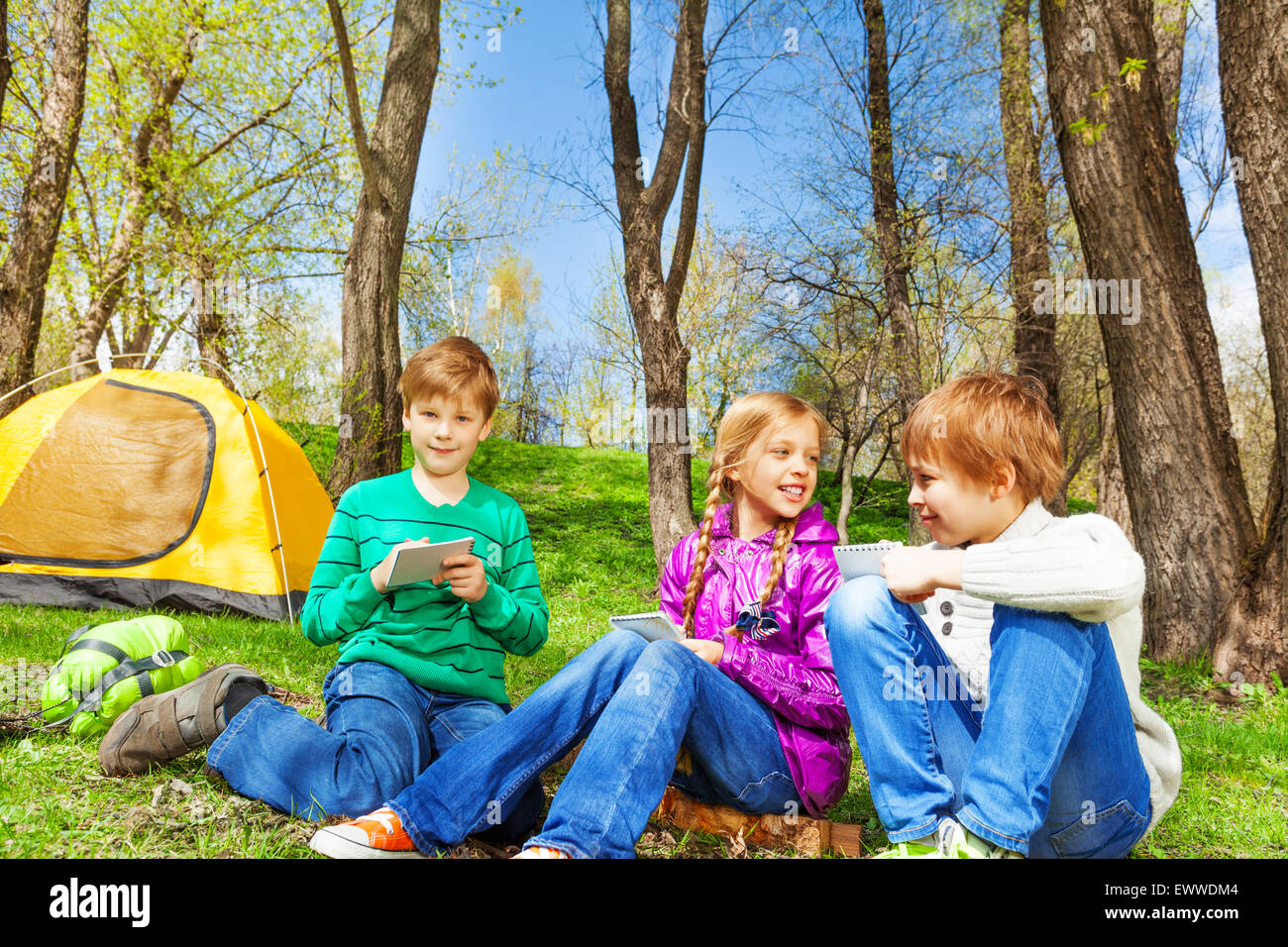 Happy kids resting together sit near yellow tent Stock Photo - Alamy