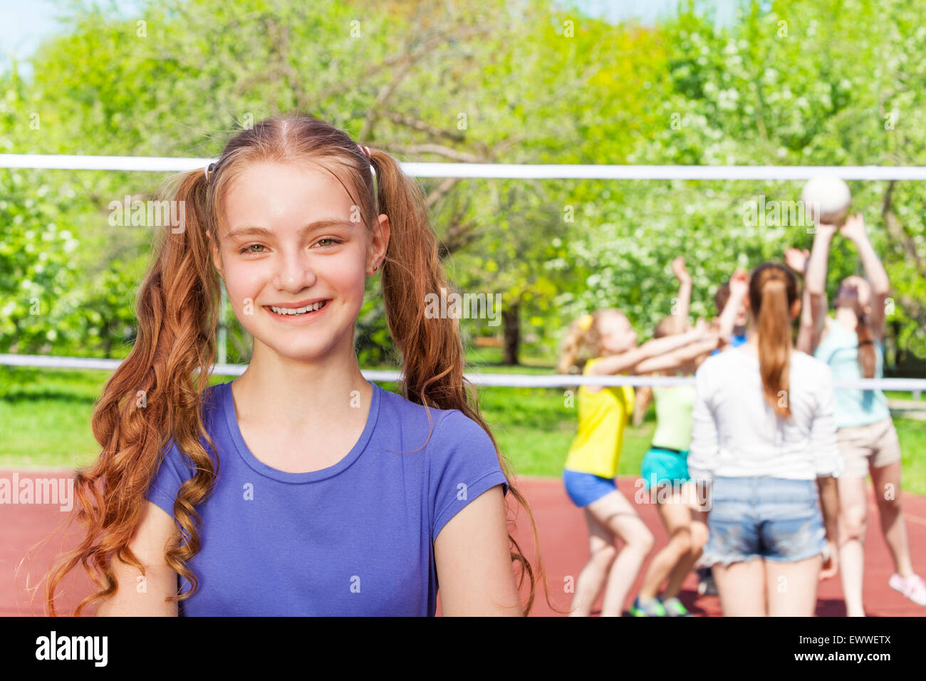 Smiling girl with classmates playing volleyball Stock Photo - Alamy