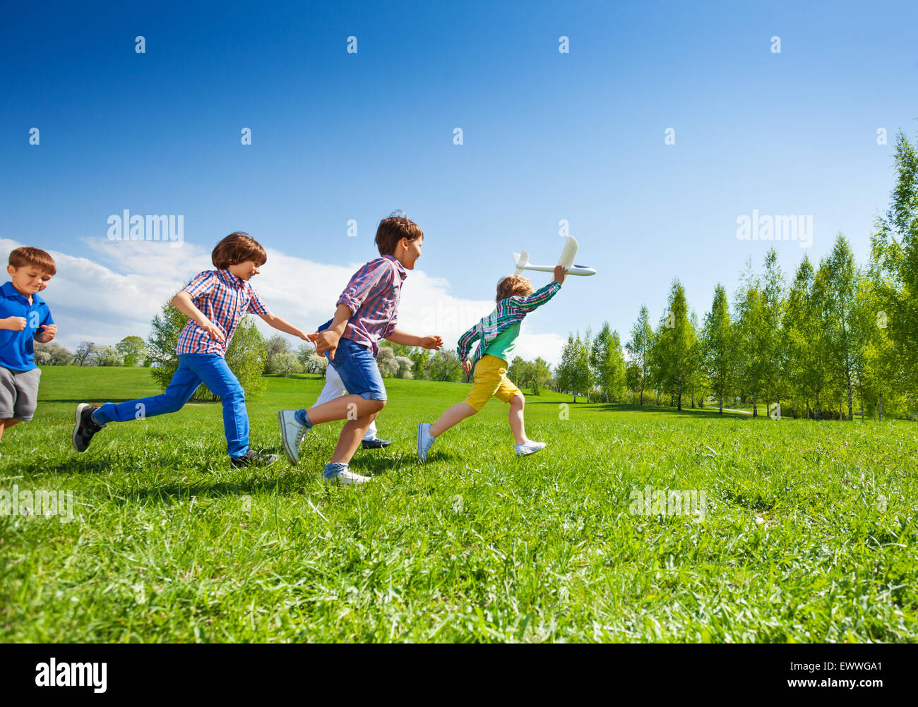 Boy with airplane and following him children run Stock Photo - Alamy